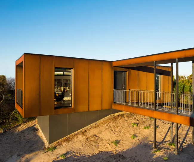 Red-steel beach house inspired by shipwrecks